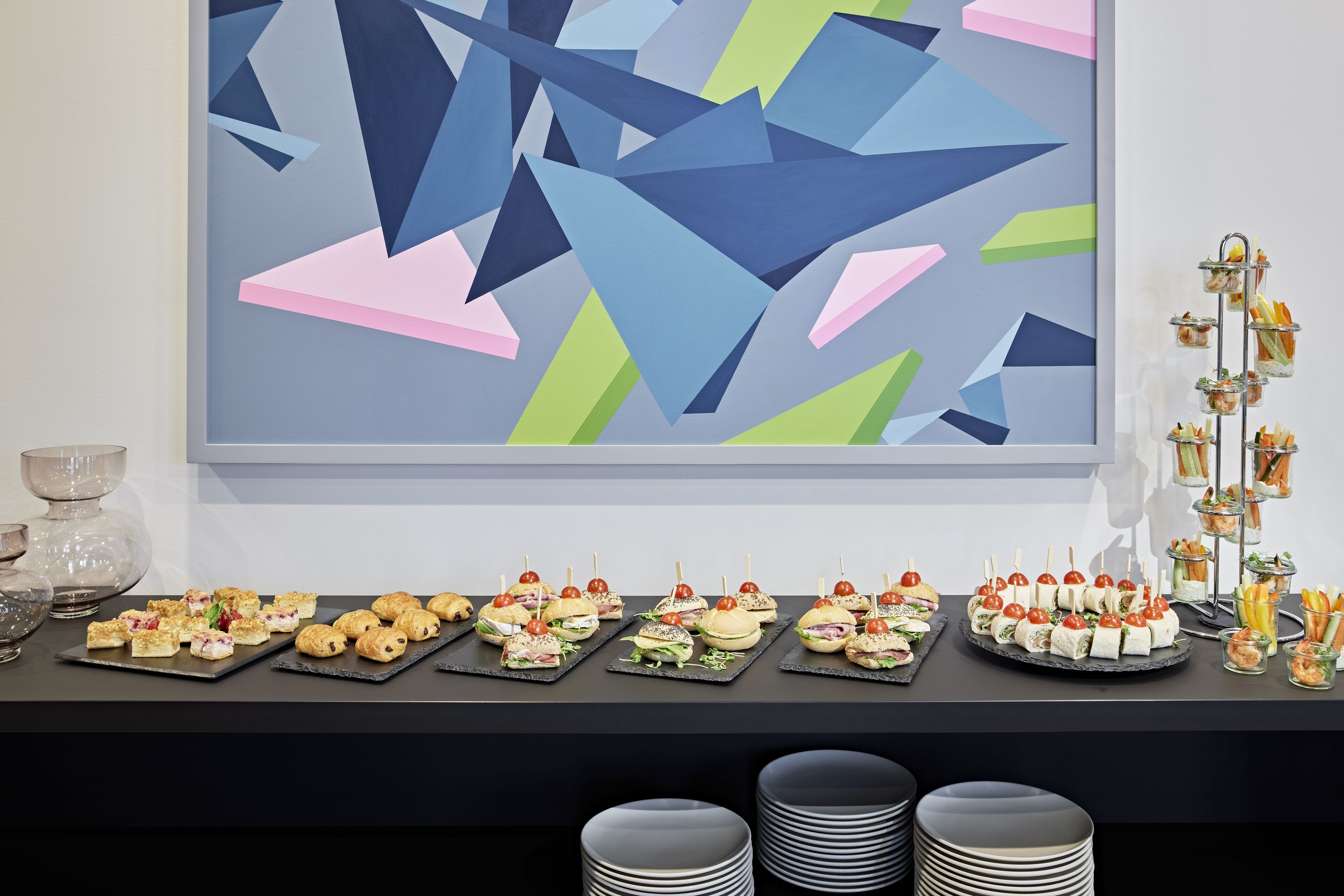 Uma mesa de buffet com diversos alimentos e um elemento decorativo na parede.