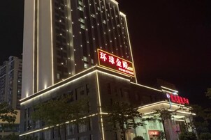 Hotel com letreiros iluminados, vários andares e fachada bem iluminada.