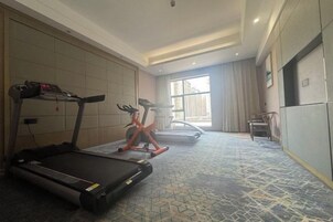 Quarto de hotel com esteira, bicicleta ergométrica e uma grande janela.