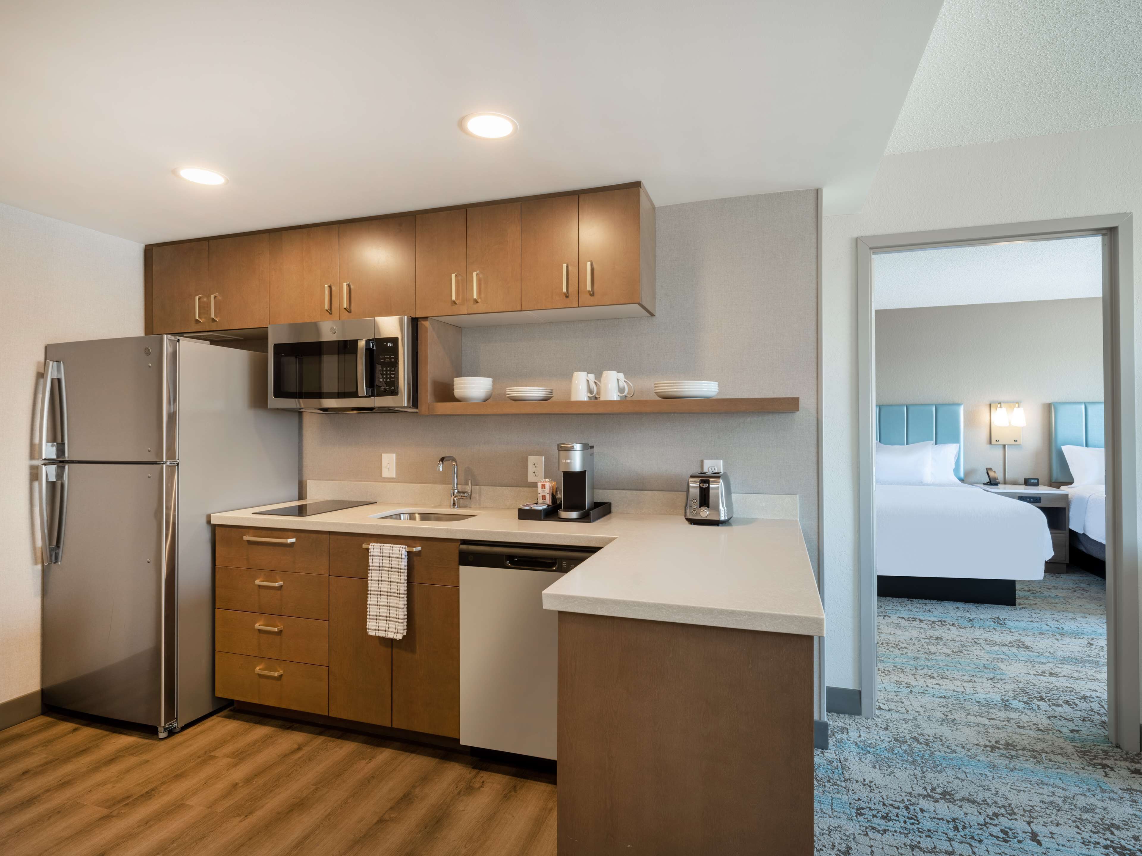 Quarto de hotel compacto com cozinha compacta, incluindo frigorífico, micro-ondas e máquina de café.