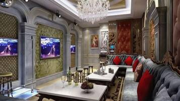 Interior luxuoso com um lustre imponente, área de estar confortável e uma tela de televisão.