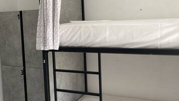 Uma cama beliche com escada, um guarda-roupa e uma cortina.