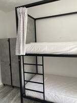 Uma cama beliche com escada, um guarda-roupa e uma cortina.