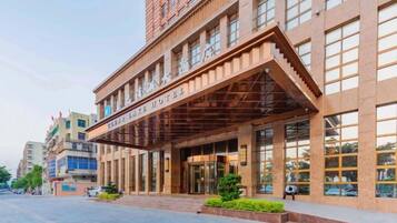 Um hotel com fachada moderna, grandes janelas e área de entrada coberta.