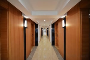 Um corredor comprido e estreito, com paredes de madeira e piso lustroso, que leva a uma série de portas.