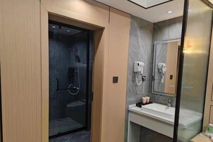 Uma casa de banho moderna com cabine de duche em vidro, toucador com espelho e dispensador de toalhas.
