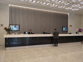 Bancada de recepção com design moderno, uma TV de tela plana e um painel digital.