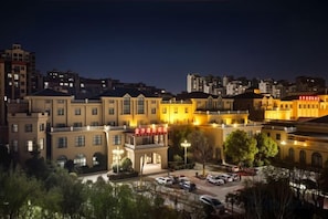 Um hotel com vários andares, área de estacionamento e fachada bem iluminada.
