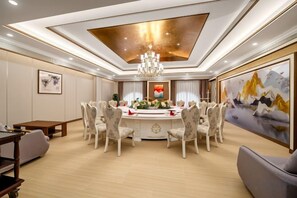 Uma sala de jantar com uma mesa redonda, cadeiras e um candelabro.