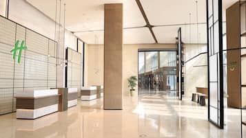 Um lobby moderno com uma receção, um pilar grande e vista para a área de convívio.