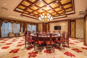 Uma sala de conferências com uma mesa redonda, cadeiras e um candelabro.