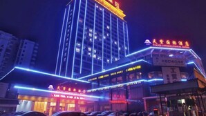 Hotel com vários andares, letreiros iluminados e estacionamento em frente.