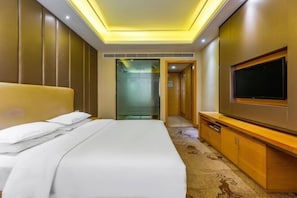 Quarto de hotel com uma cama, televisão e guarda-roupa.