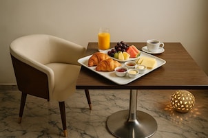 Disposição para o café da manhã com croissants, frutas, queijos e bebidas sobre uma mesa.