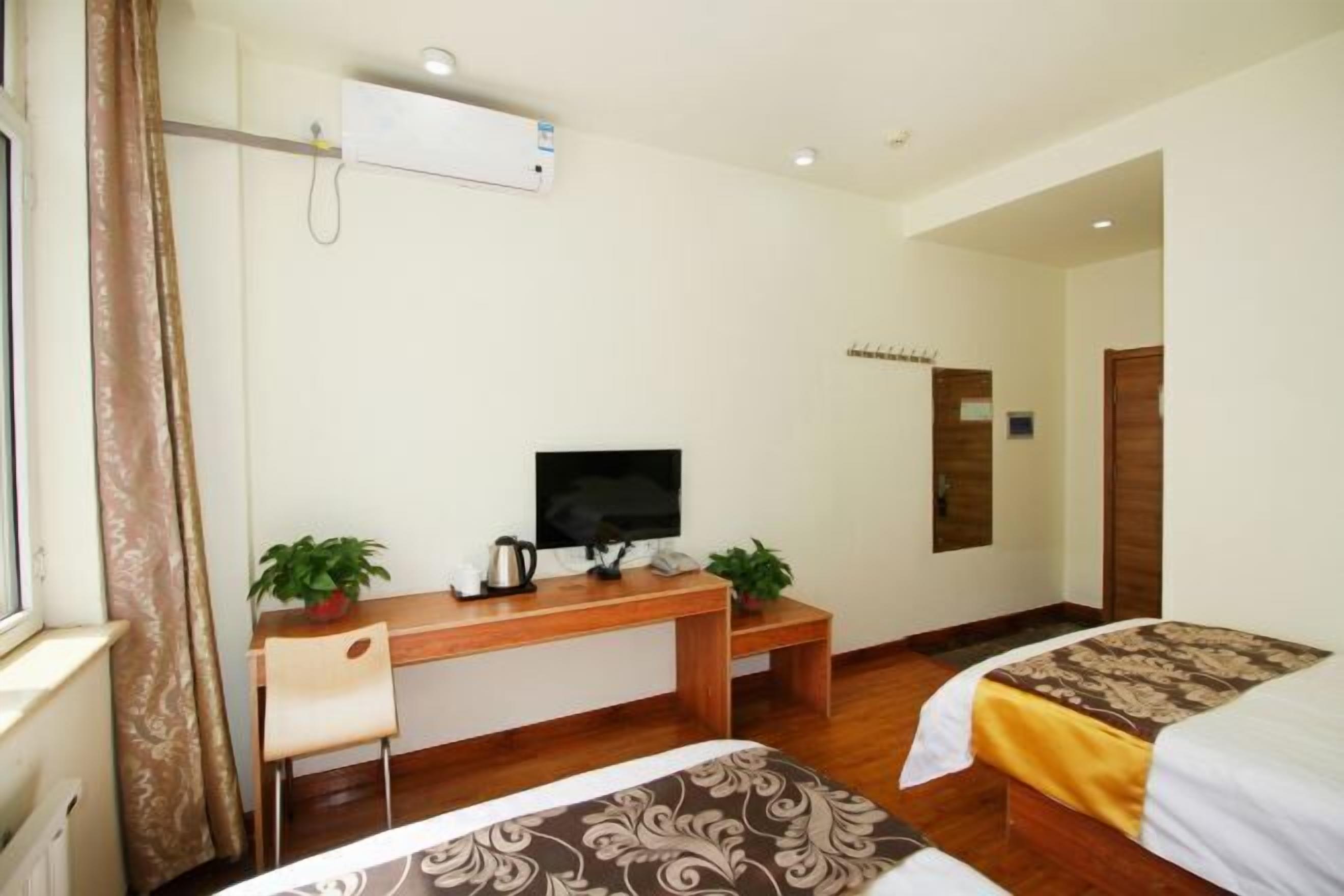 Quarto de hotel com cama, escrivaninha, televisão, cadeira e mesa pequena.