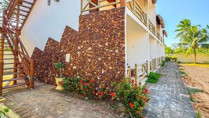 Um edifício de dois andares com fachada de pedra, escadaria de madeira e telhado de colmo.