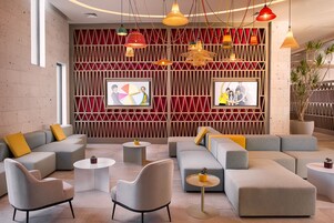 Uma área de estar moderna com sofás, poltronas e mesas redondas.