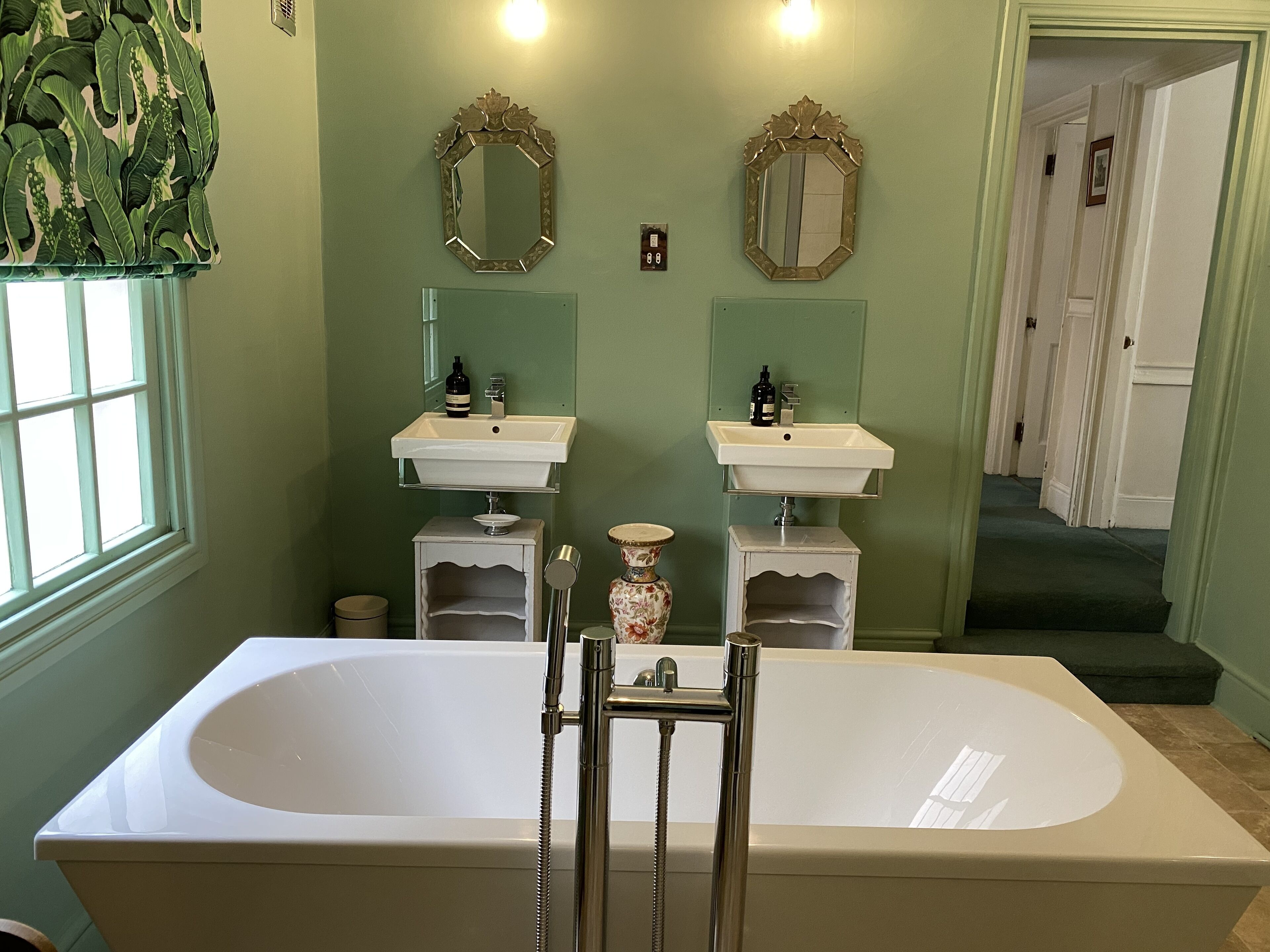 Casa de banho com uma banheira grande, duas pias e espelhos decorativos.