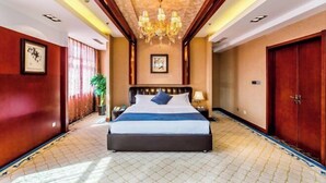 Quarto de hotel com uma cama grande, um candelabro e um guarda-roupa de madeira.
