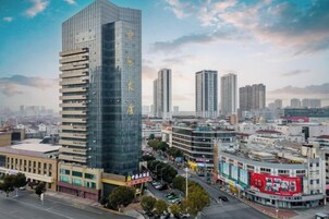 Um edifício alto com vários andares, cercado por outros edifícios e uma rua movimentada.