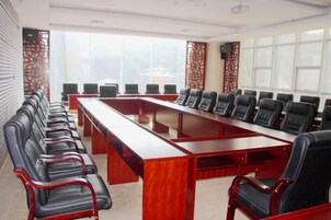 Uma sala de conferências com uma mesa comprida e várias cadeiras, janelas amplas e painéis decorativos.