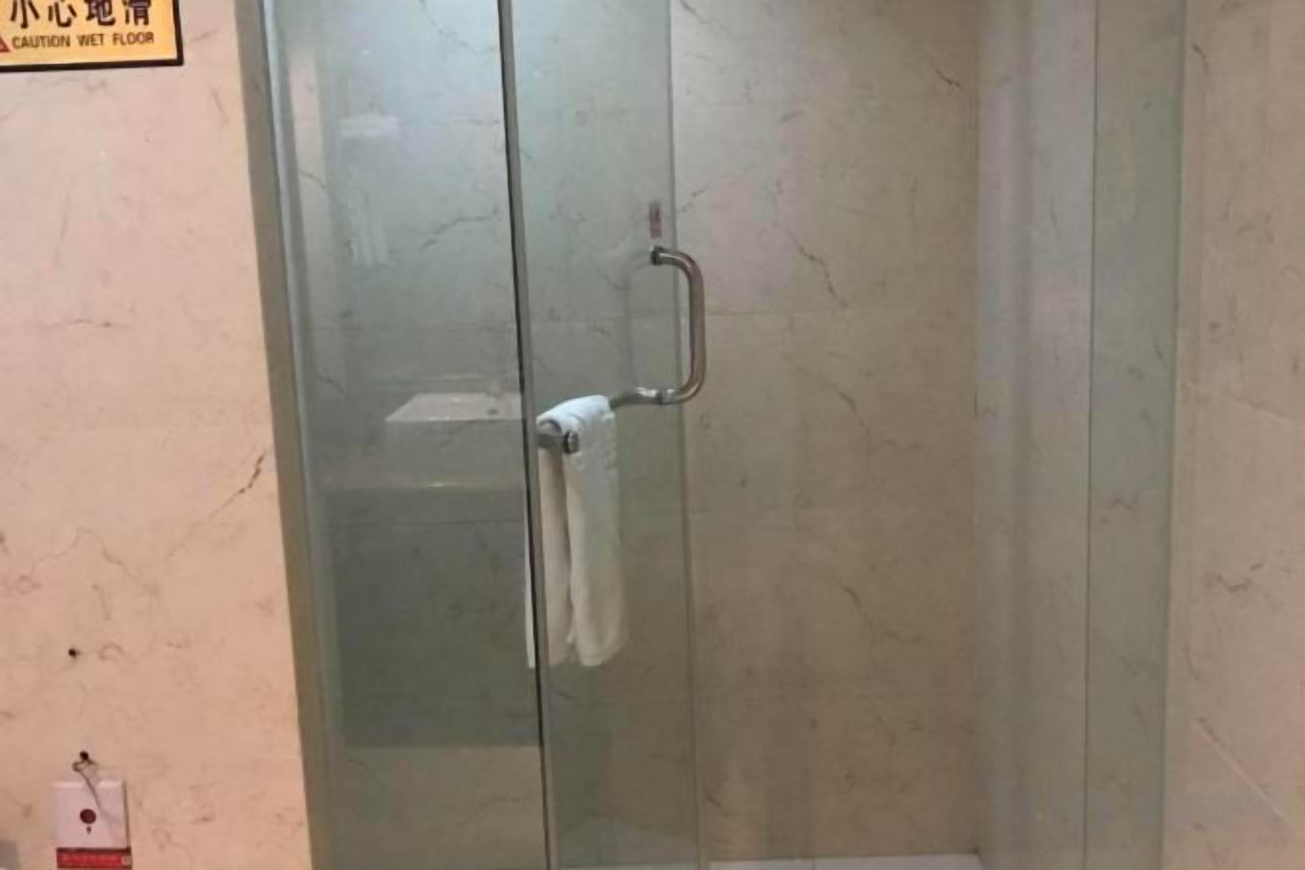 Box de chuveiro com paredes de vidro e uma toalha pendurada no puxador da porta.