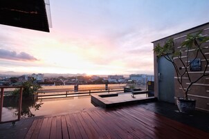 Um deck de madeira com vista para o horizonte urbano ao pôr do sol.
