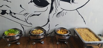 Disposição de buffet com diversos alimentos em recipientes de metal.