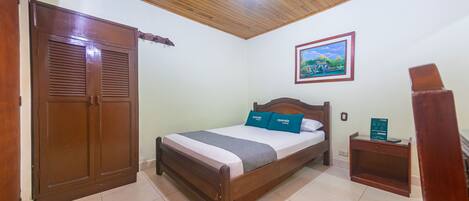 Quarto com cama de madeira, mesa de cabeceira, guarda-roupa e um quadro na parede.