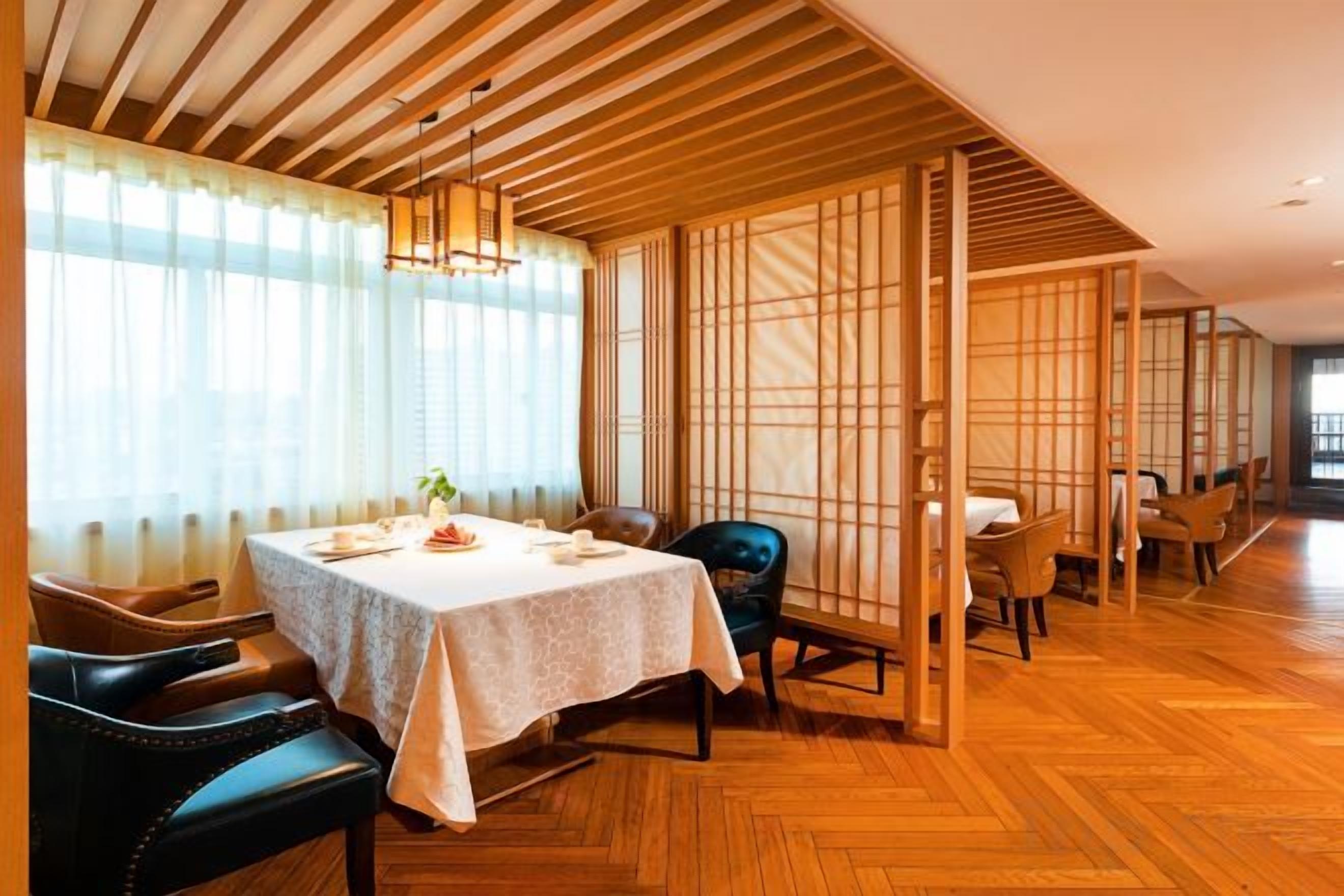 Uma sala de jantar tradicional japonesa, com piso de madeira, uma mesa posta para dois e uma porta de correr.