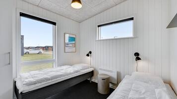 Quarto com duas camas, uma janela, um radiador e um quadro na parede.