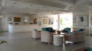 Um hall amplo com móveis de vime, um balcão de recepção e obras de arte nas paredes.