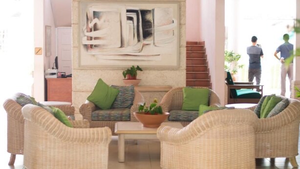 Uma sala de estar com móveis de vime, uma mesa de centro e um quadro na parede.