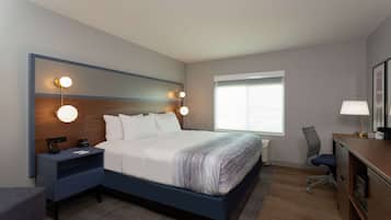 Quarto de hotel moderno com uma cama grande, mesas de cabeceira, uma escrivaninha e uma cadeira.