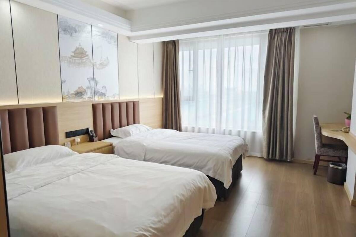Quarto de hotel com duas camas, uma escrivaninha e uma cadeira.