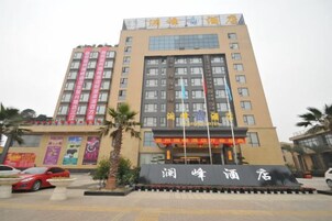 Um hotel com vários andares, entrada imponente e placas de identificação.