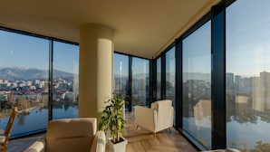 Uma sala de estar moderna com grandes janelas, uma planta em vaso e dois sofás.