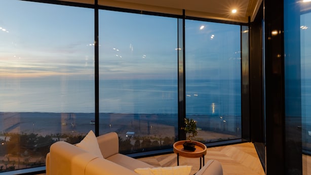 Sala de estar moderna com uma grande janela dando para uma vista urbana.