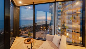 Sala de estar moderna com uma grande janela com vista para a paisagem urbana.