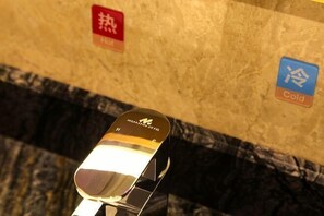 Um objeto metálico, possivelmente parte da decoração ou mobiliário de um espaço, com superfície refletora.