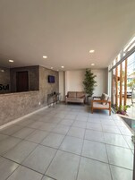 Um hall amplo com balcão de recepção, um sofá e uma poltrona.