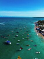 Vista aérea de uma praia com muitos barcos e guarda-sóis.