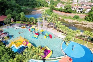 Parque aquático com vários toboáguas e piscinas, cercado por vegetação e um rio.