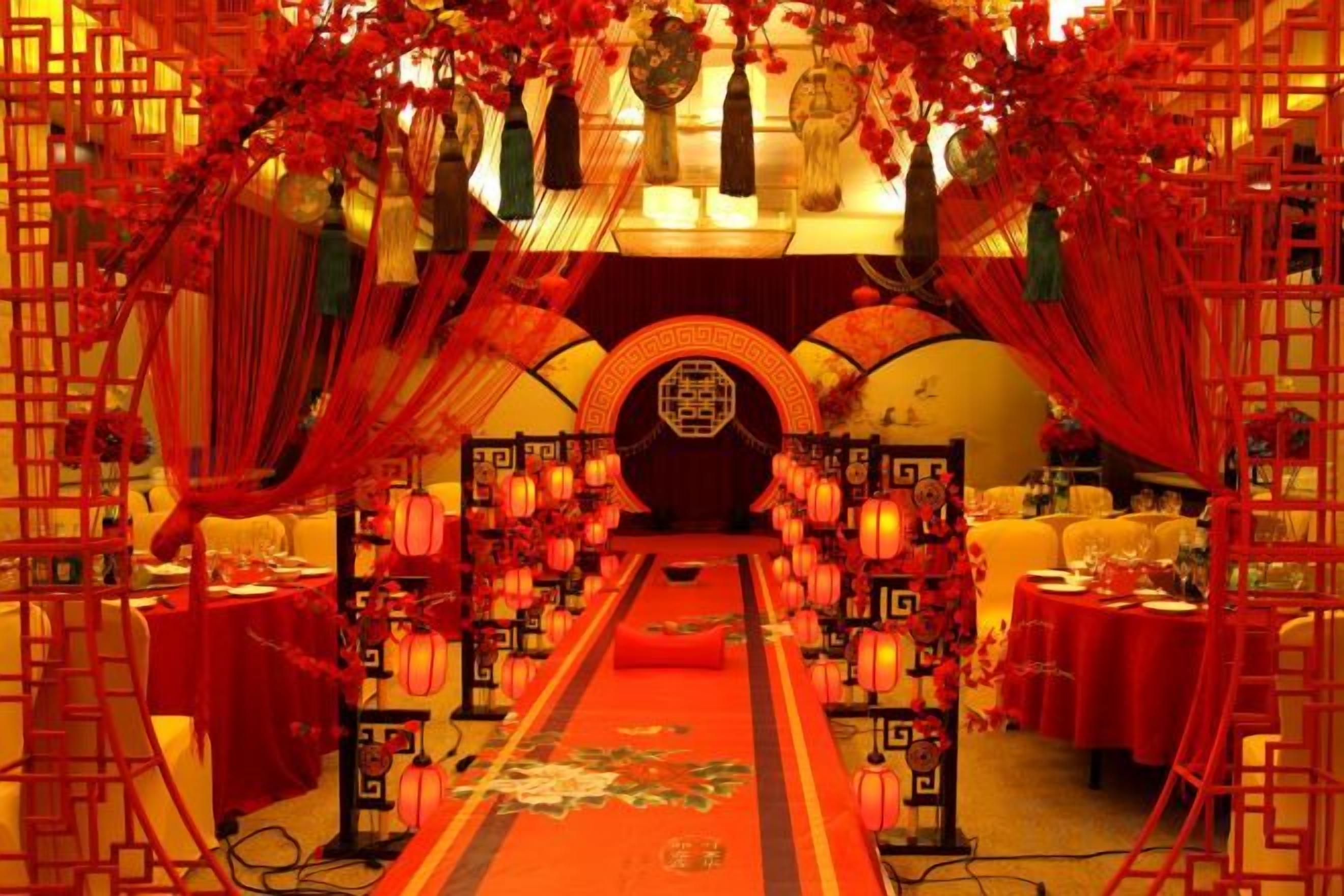 Corredor decorado com lanternas vermelhas, adornos tradicionais chineses e um arco central.