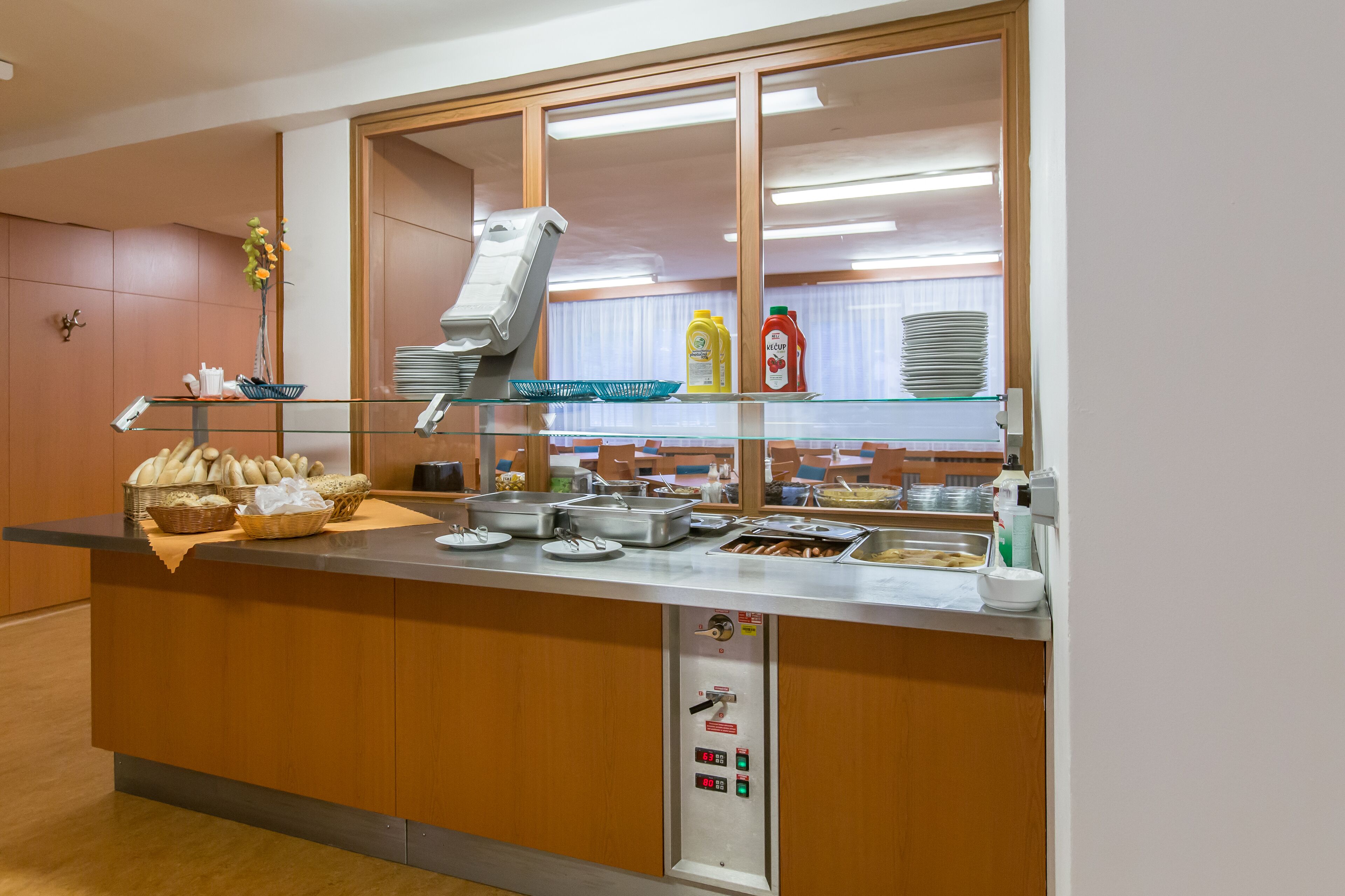 Um balcão de buffet com diversos alimentos, garrafas de temperos e uma vitrine de vidro.