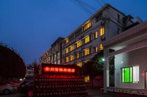 Um hotel com vários andares, uma placa chamativa e uma entrada bem iluminada.