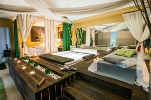 Um espaço de spa com uma banheira grande, mesa de massagem e um banco de madeira.