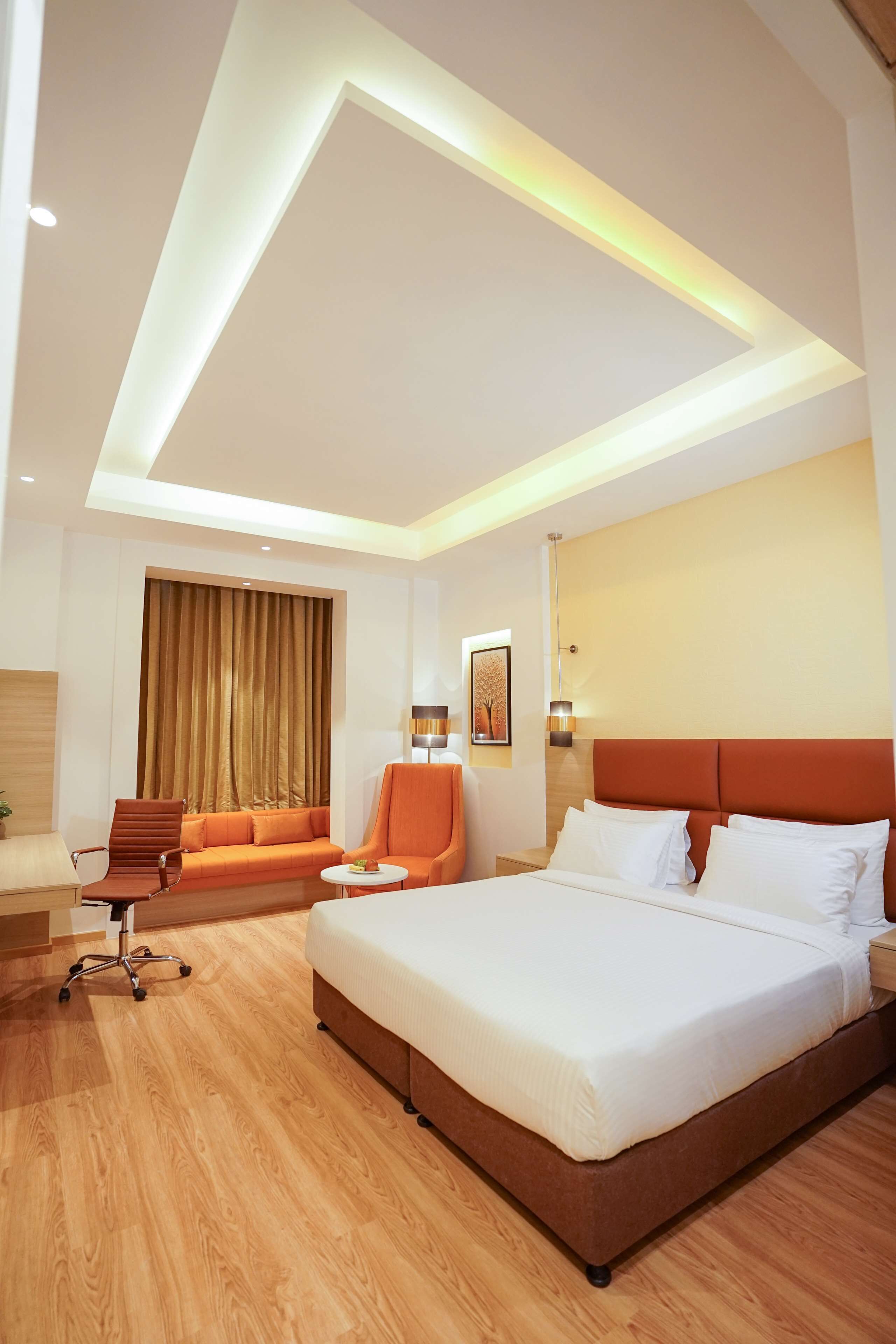 Quarto de hotel moderno com uma cama grande, um sofá, uma escrivaninha e uma cadeira.