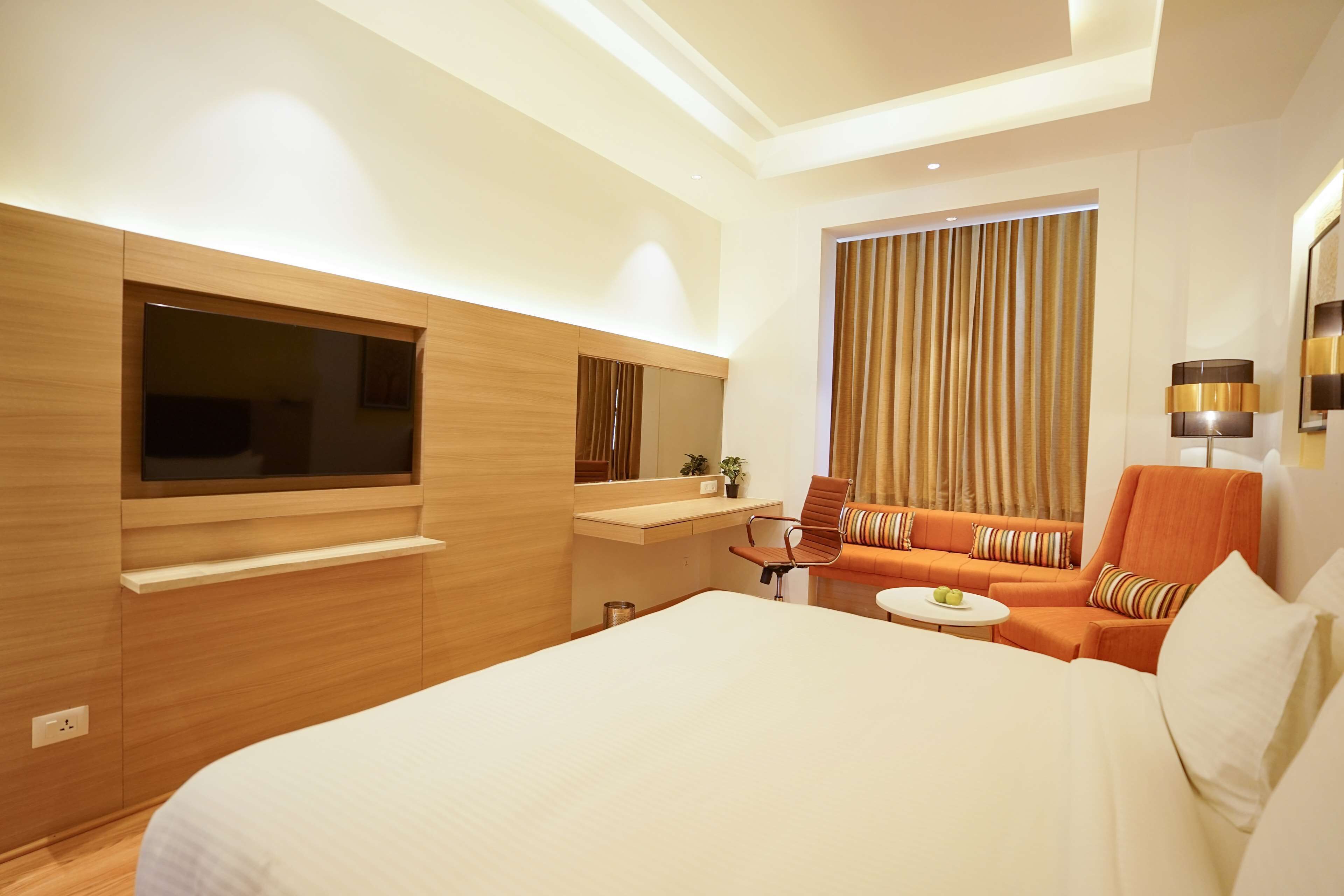 Quarto de hotel moderno com uma cama grande, um sofá, uma TV e uma mesa de trabalho.