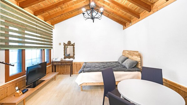 Um quarto aconchegante com cama, mesa de cabeceira, televisão e espelho.